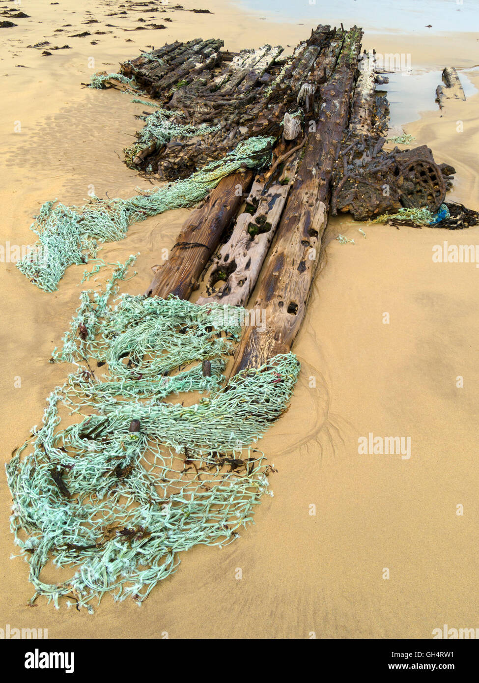 Shipwreck driftwood and old fishing net buried in sand, Balnahard Beach ...
