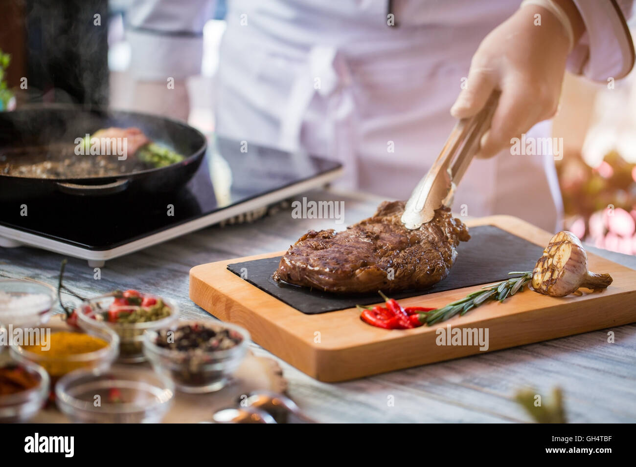 Tongs holding cooked meat Stock Photo - Alamy