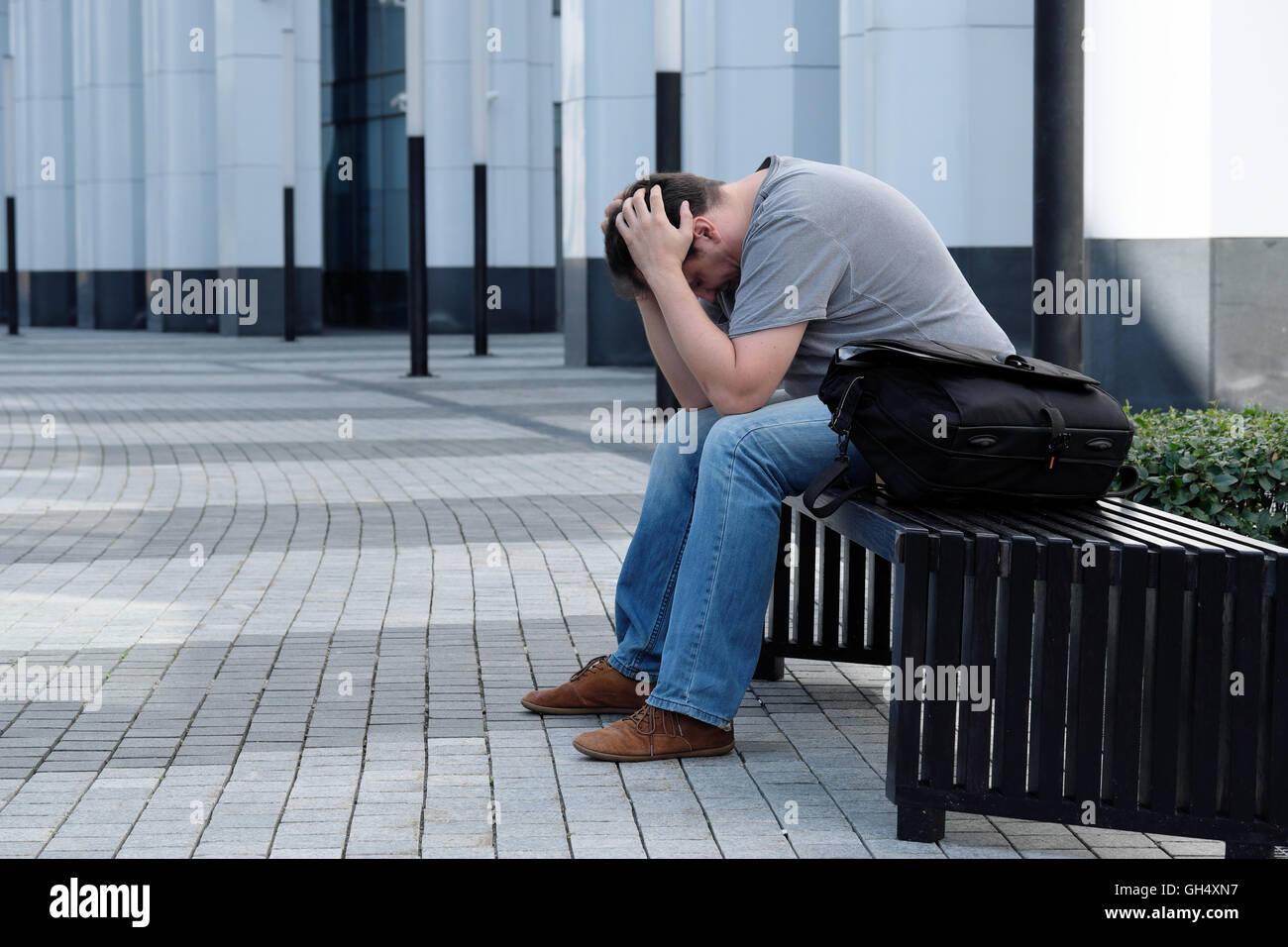 Sad man sitting in front of white office building Stock Photo - Alamy