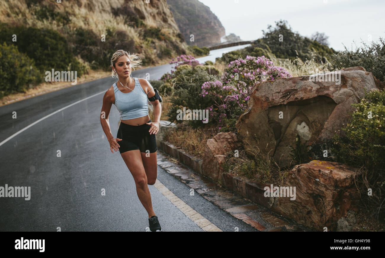 fitness woman running on the road around mountains under rain. Female ...