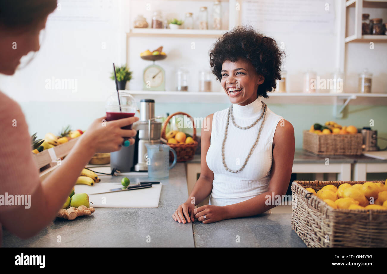 Portrait of smiling young african woman standing behind juice bar ...