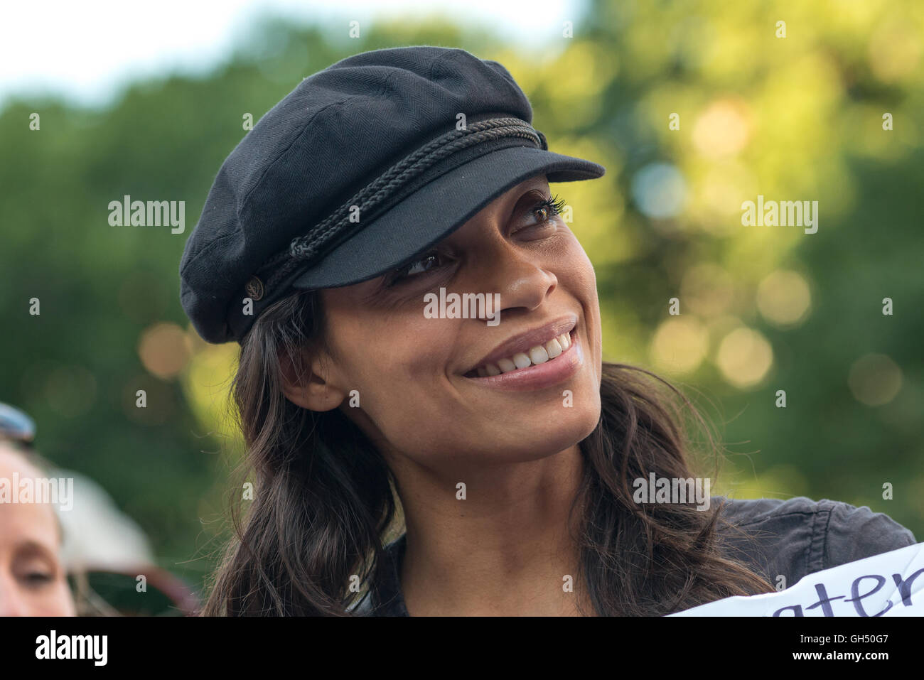 Rosario Dawson listens as one of the rally speakers (not seen) speaks ...