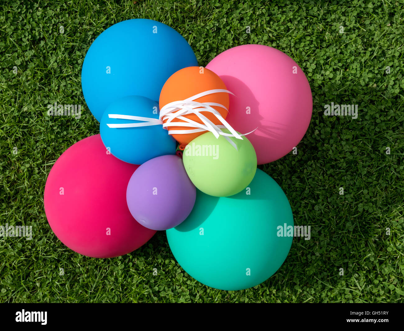 Bunch of colorful balloons on green grass Stock Photo - Alamy