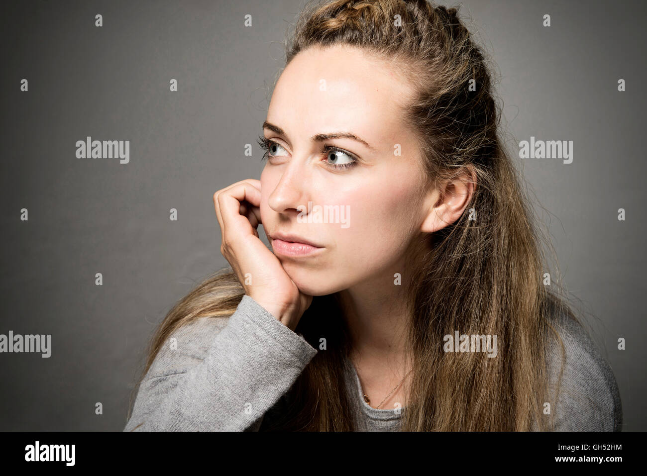 Young woman close up looking sorrowful, sad, thoughtful hand on chin ...