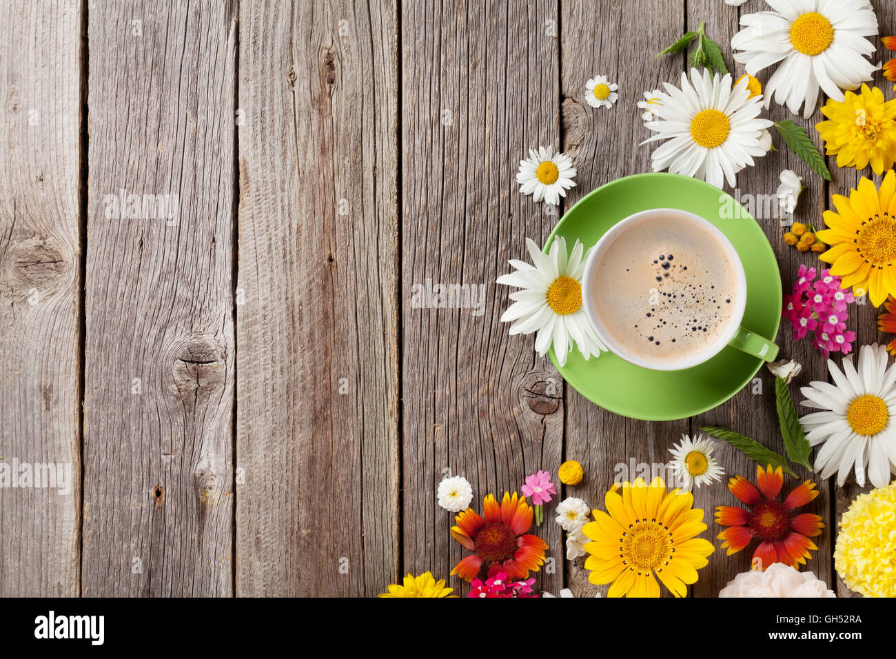 Garden flowers and coffee cup over wooden table background. Backdrop ...