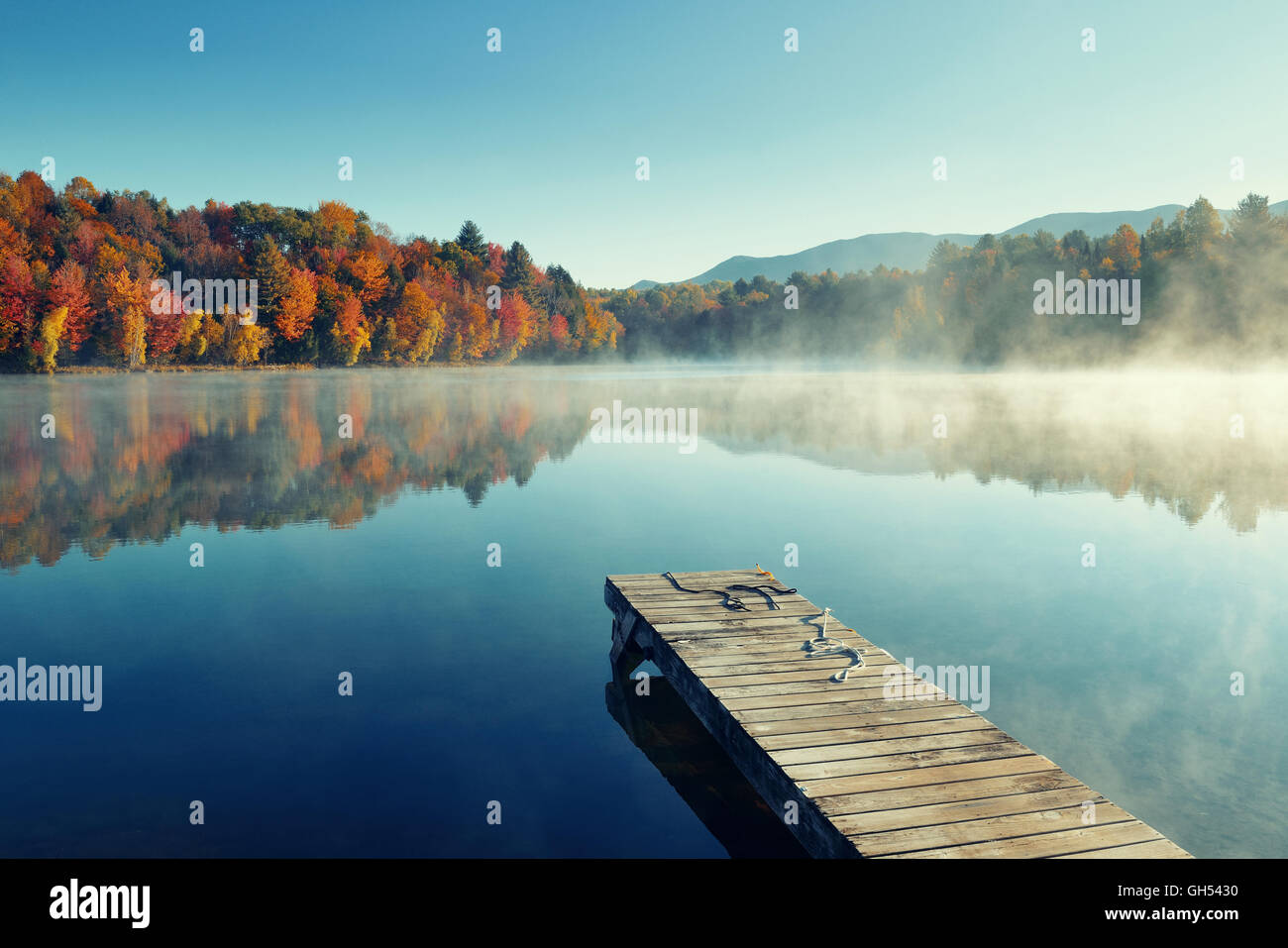 Autumn foliage and fog lake in morning with boat dock Stock Photo - Alamy