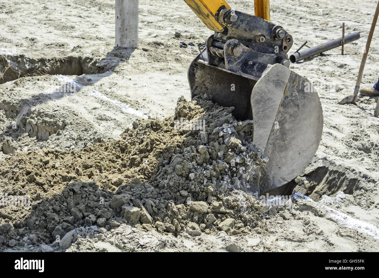 Excavator in a situation digs holes in the sandy ground Stock Photo - Alamy
