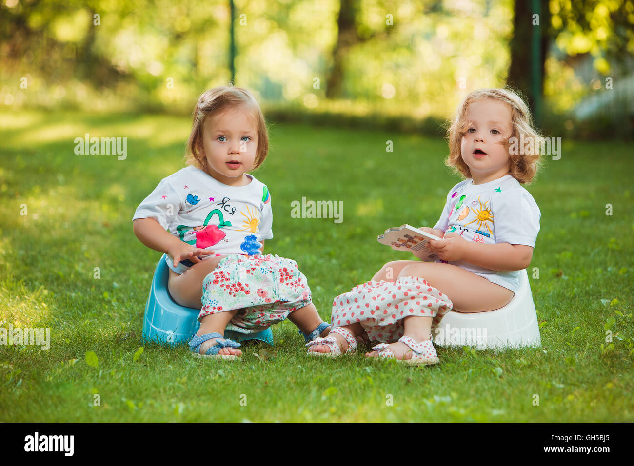 The two little baby girls sitting on pots Stock Photo - Alamy