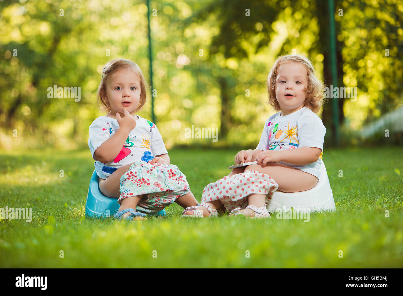 The two little baby girls sitting on pots Stock Photo - Alamy