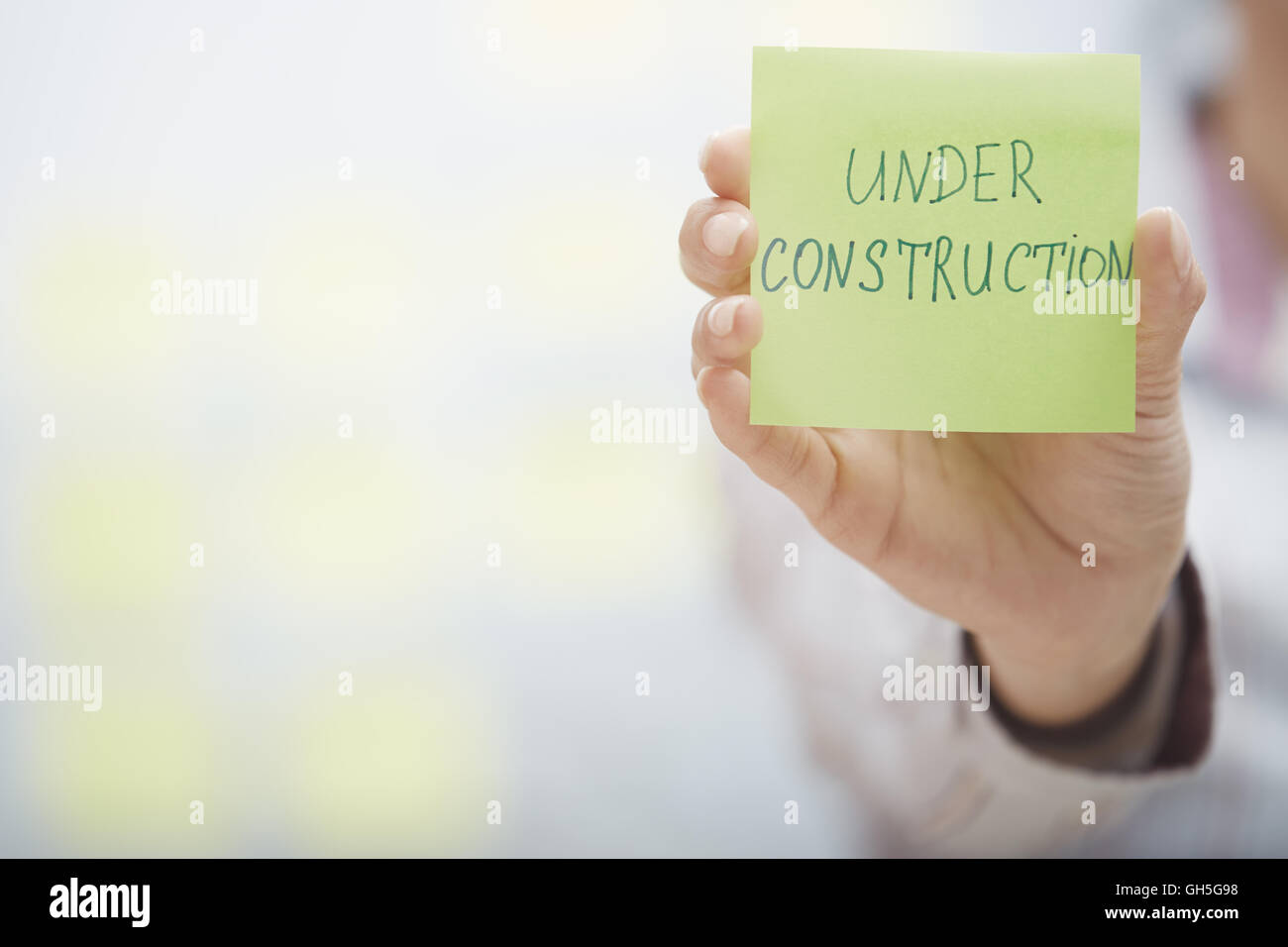 Woman holding sticky note with Under construction text Stock Photo - Alamy