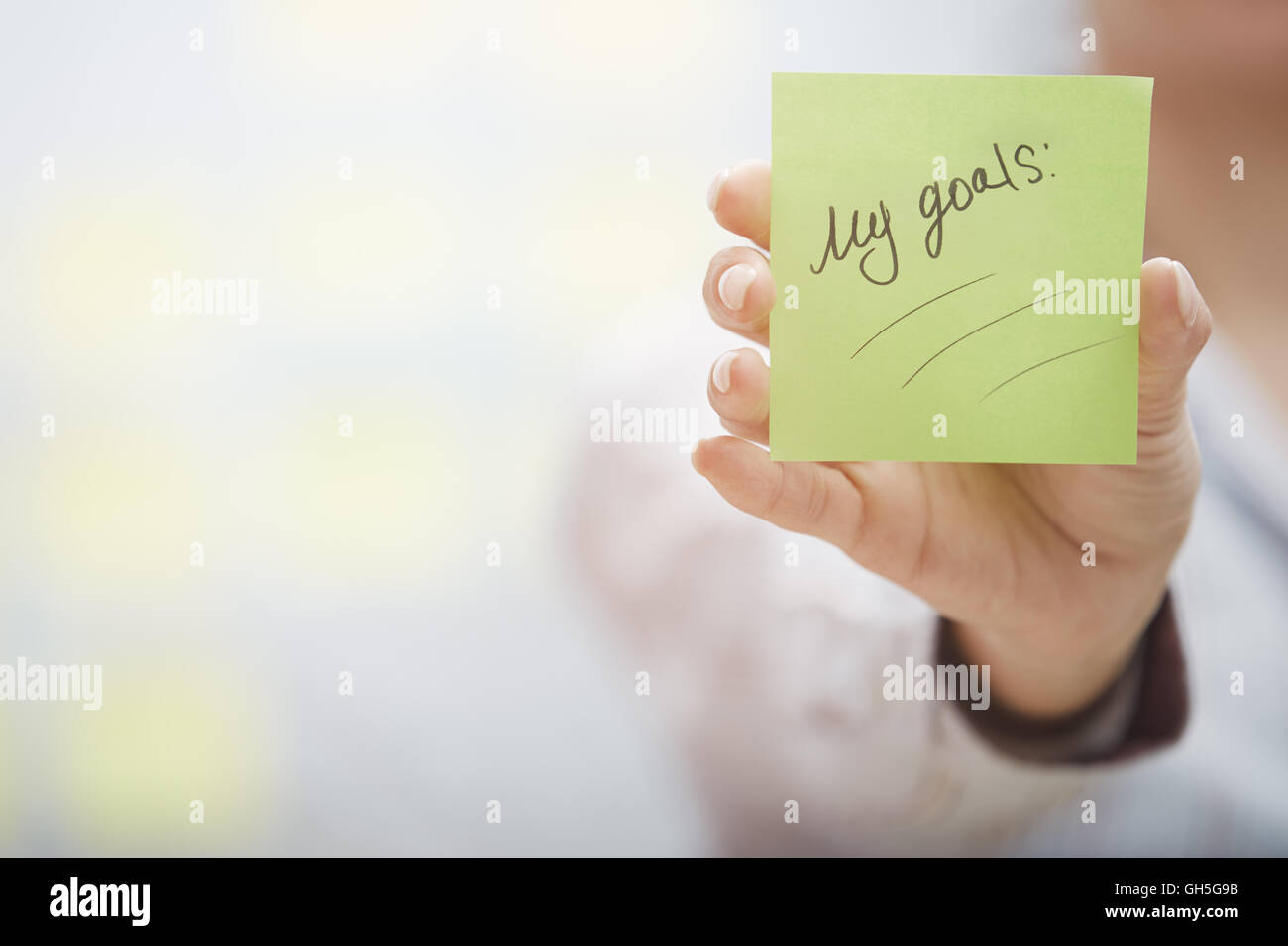 Woman holding sticky note with goals planning Stock Photo - Alamy