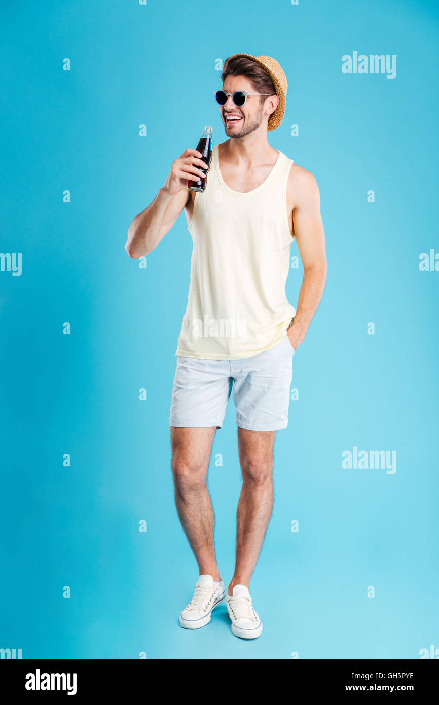 Full length of cheerful young man standing and drinking soda Stock ...