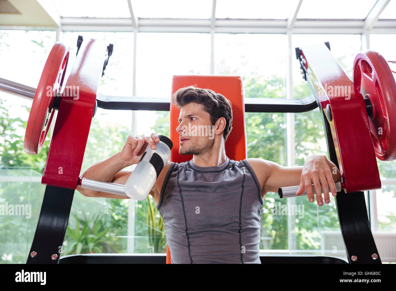 Portrait of a handsome tired fitness man resting on the bench at gym ...