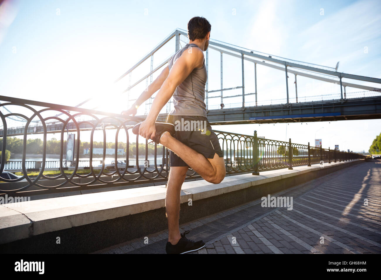 Side view of a handsome young sports man doing stretching leaning ...