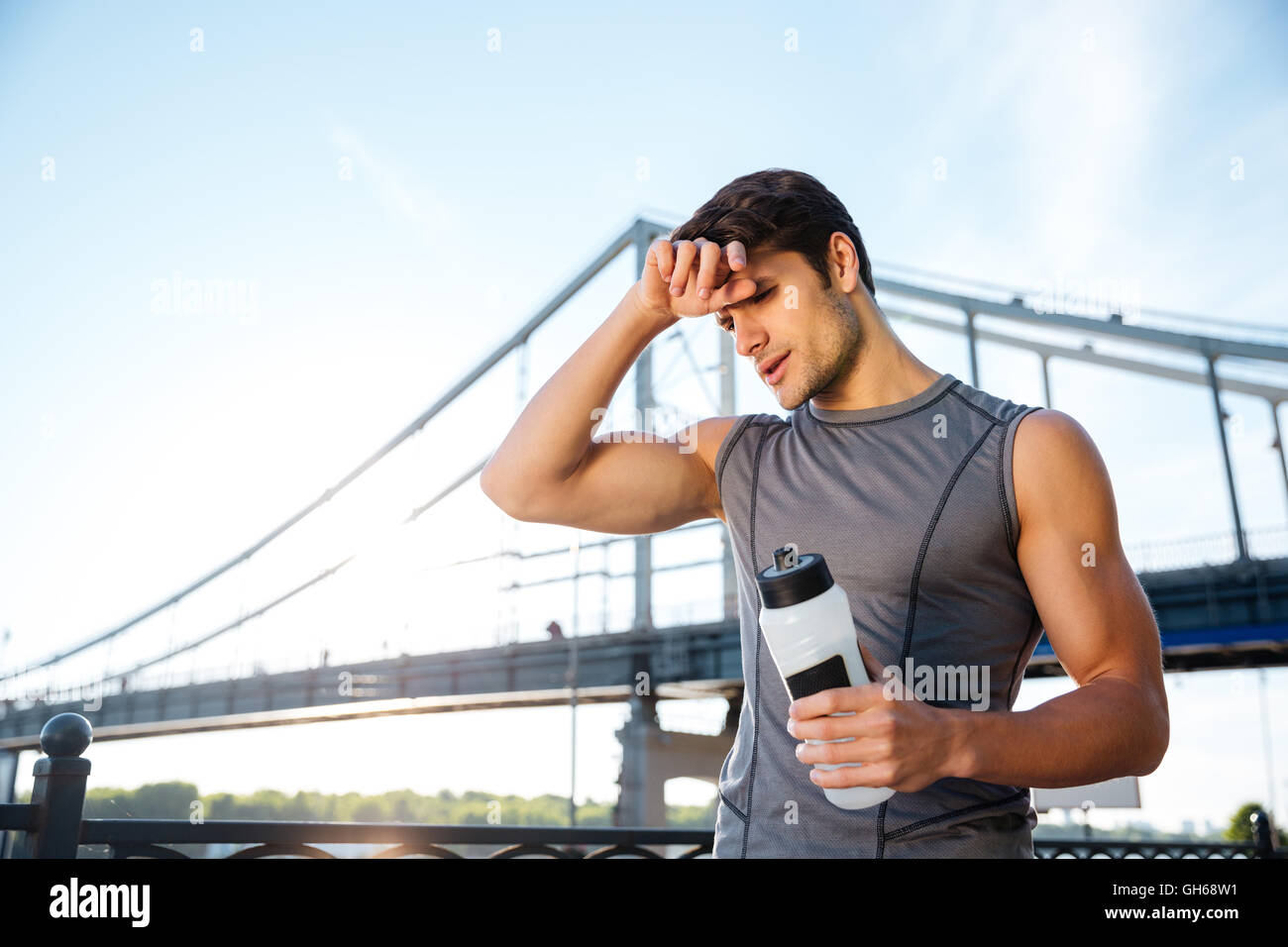 Handsome young sports man resting after running and holding water ...