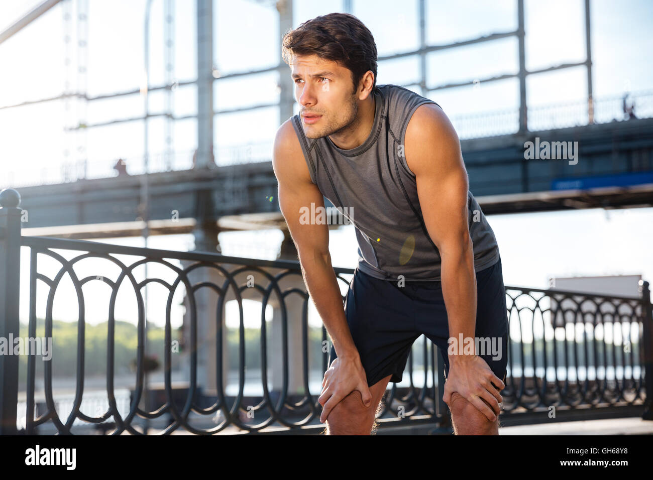 Concentrated young sports man resting after running while standing on ...