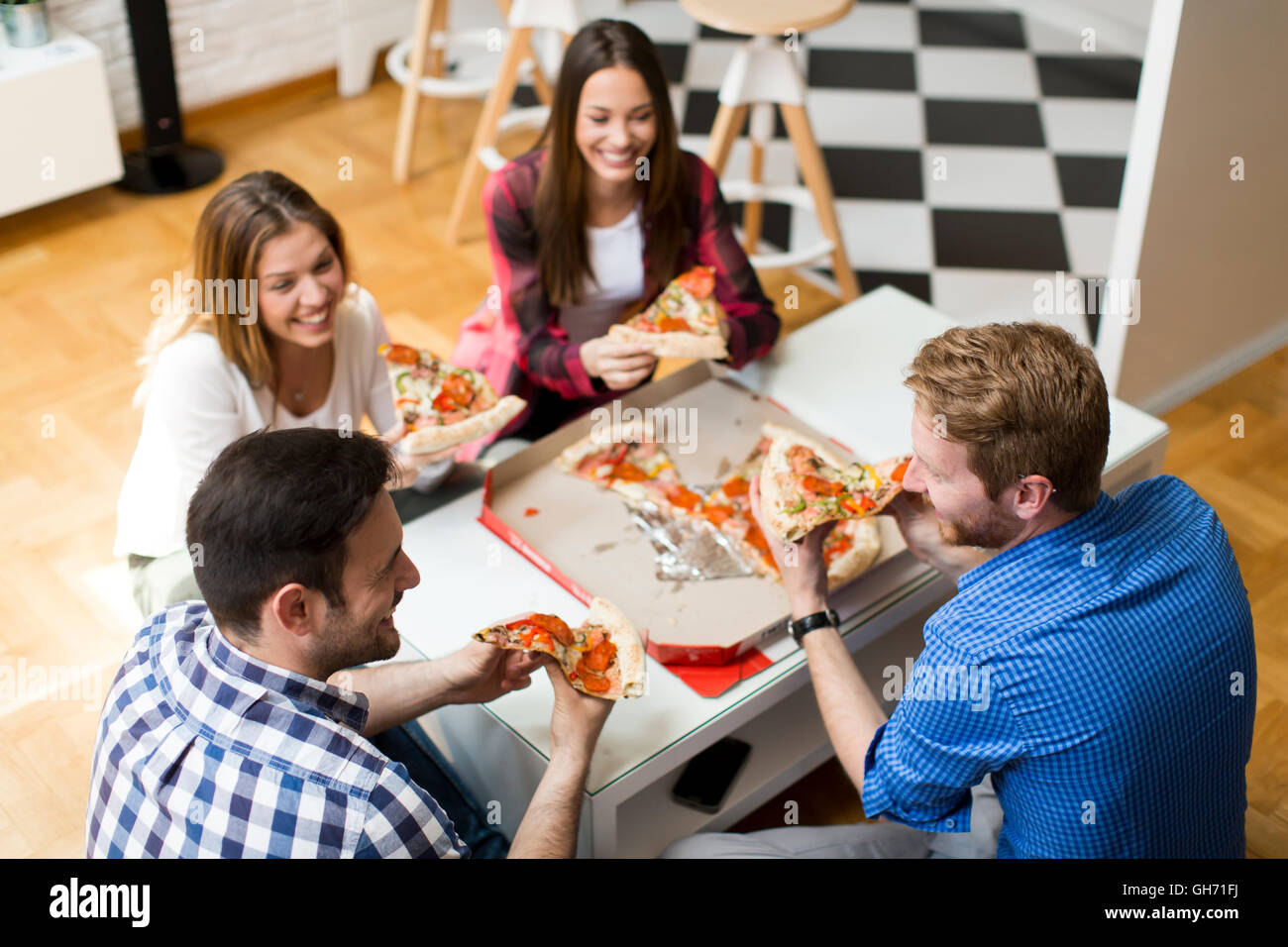 Group of young people eating pizza in th room Stock Photo - Alamy