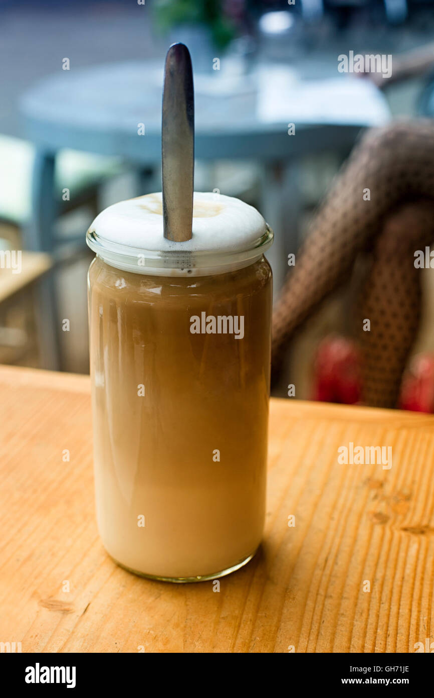 glass of coffee outside at cafe next to womans legs Stock Photo - Alamy