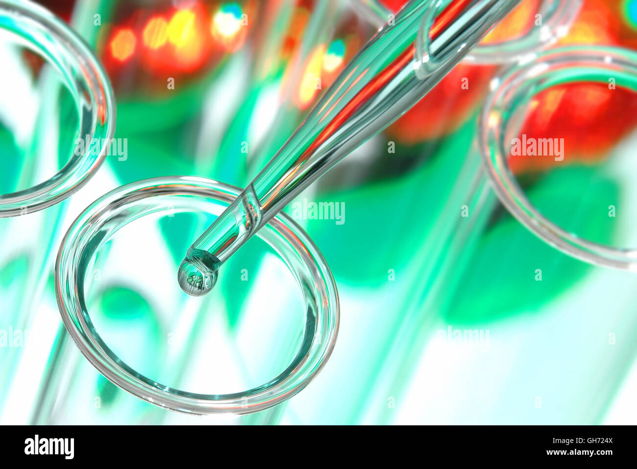 Laboratory pipette with drop of liquid over glass test tubes for a ...