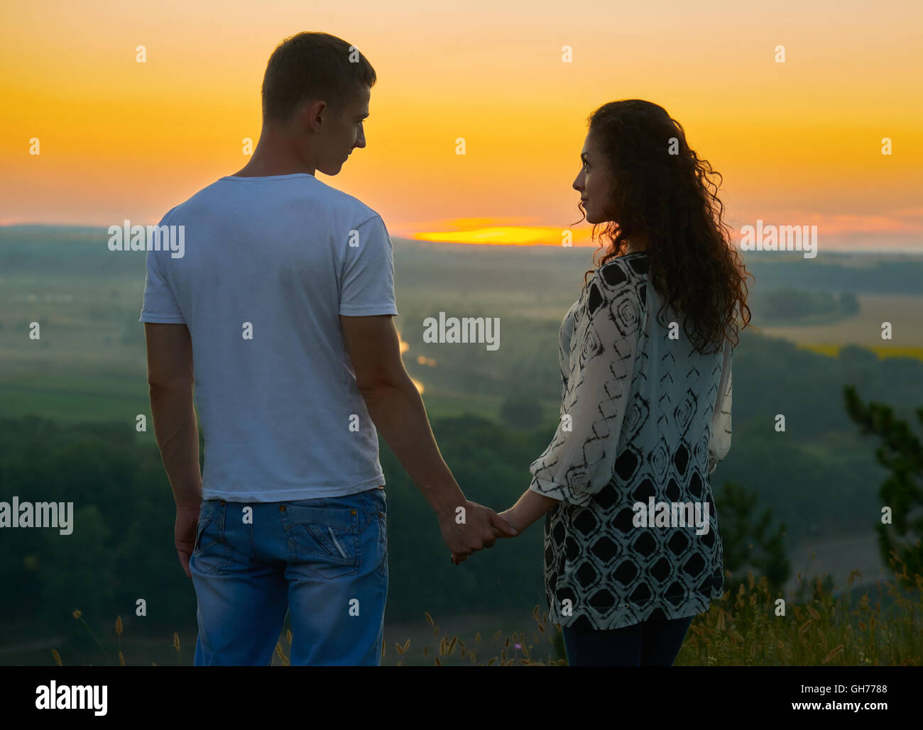 romantic couple looking into the distance at sunset on outdoor ...