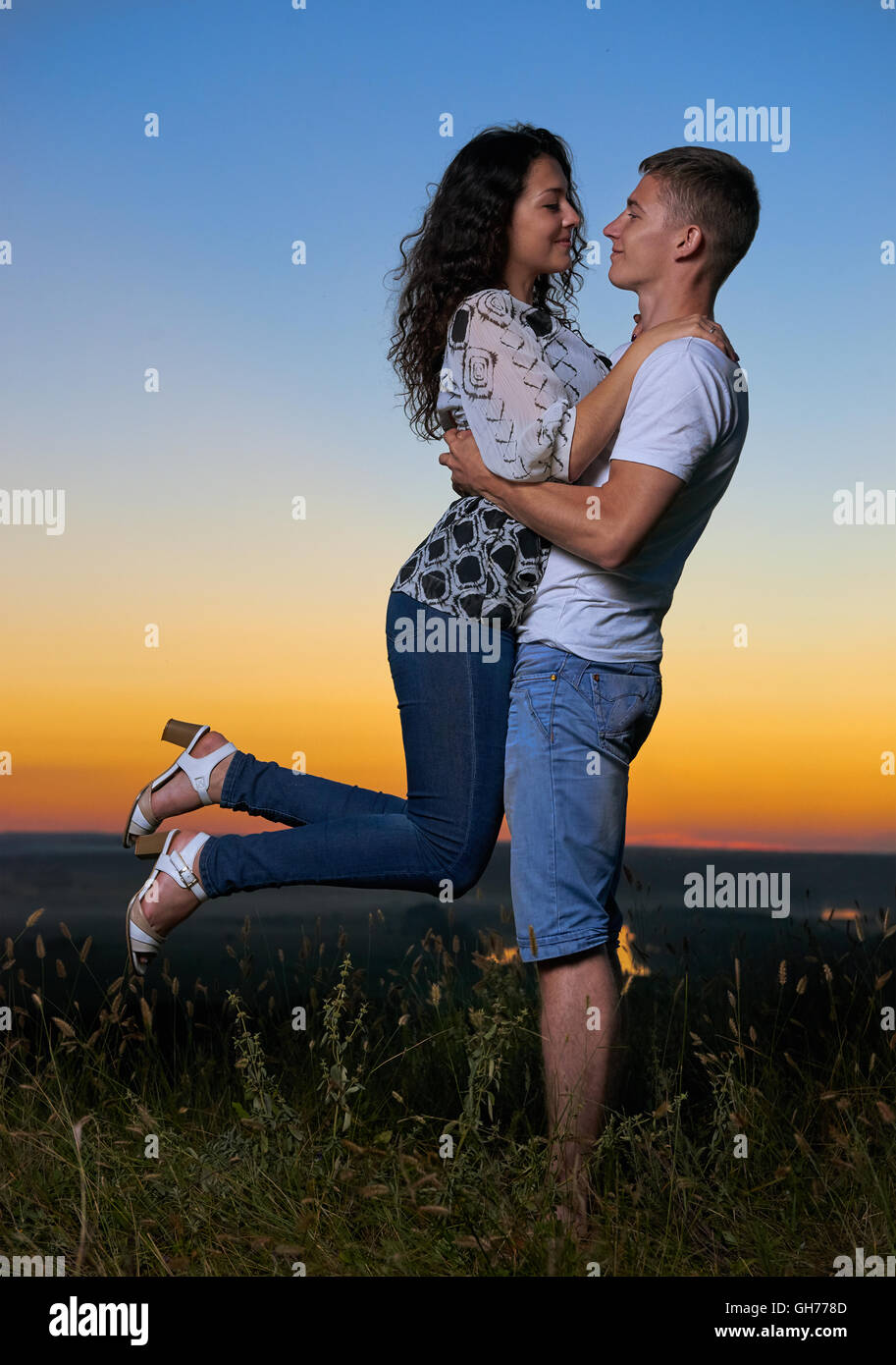 romantic couple embrace at sunset, beautiful landscape and dark sky ...