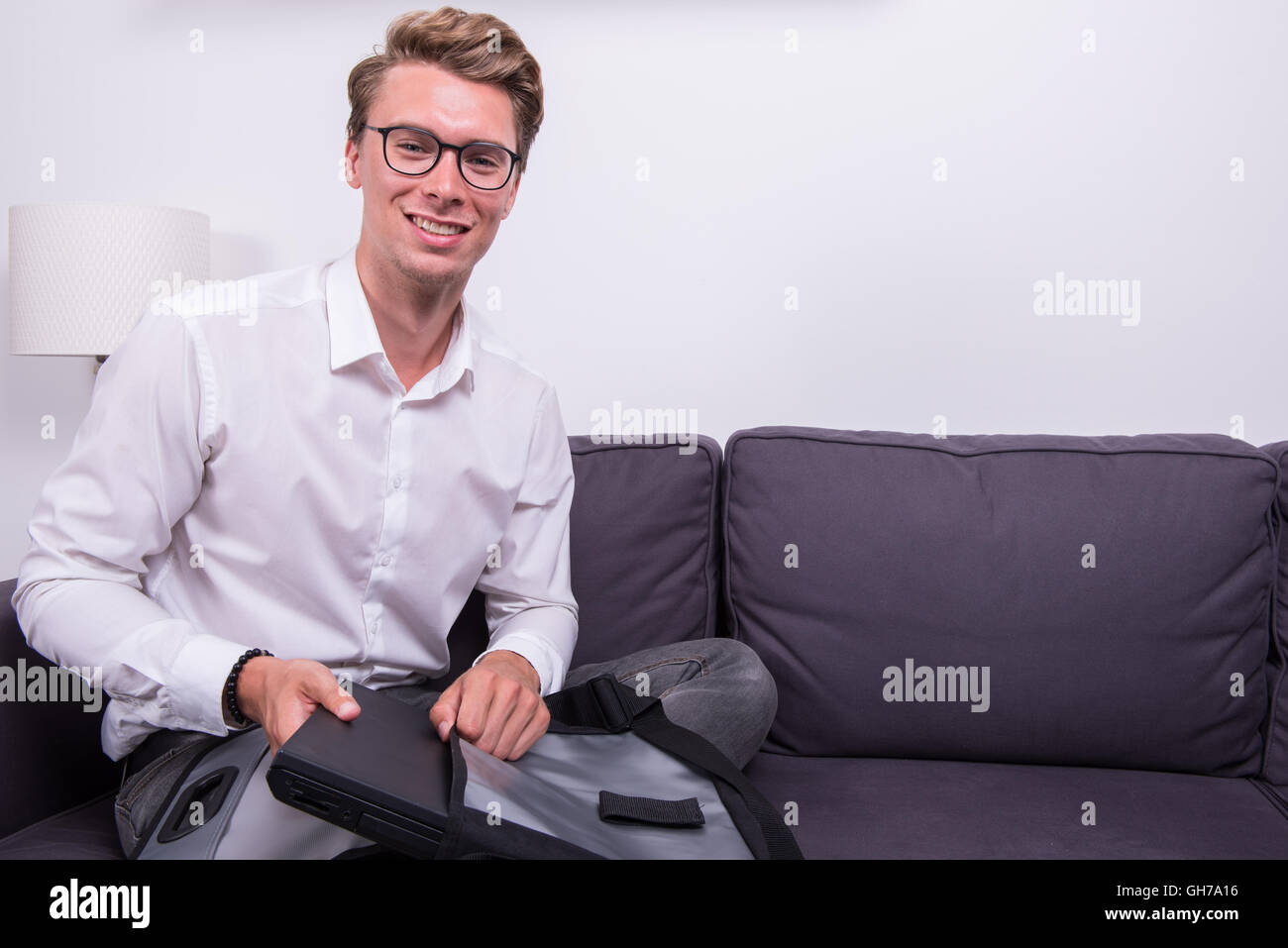 young smiling business man packing his bag on couch Stock Photo - Alamy