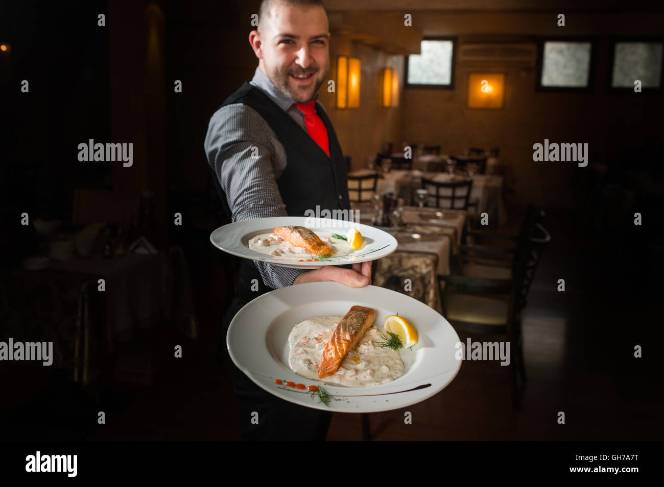 Waiter carrying a plate with meat dish Stock Photo - Alamy