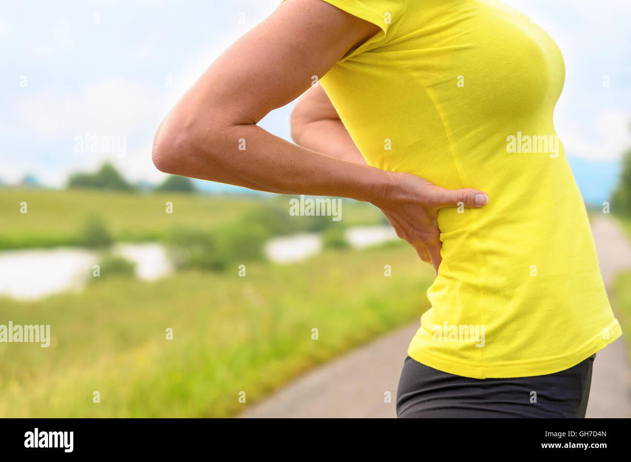 Shapely fit young woman in a colorful yellow top stretching with her ...