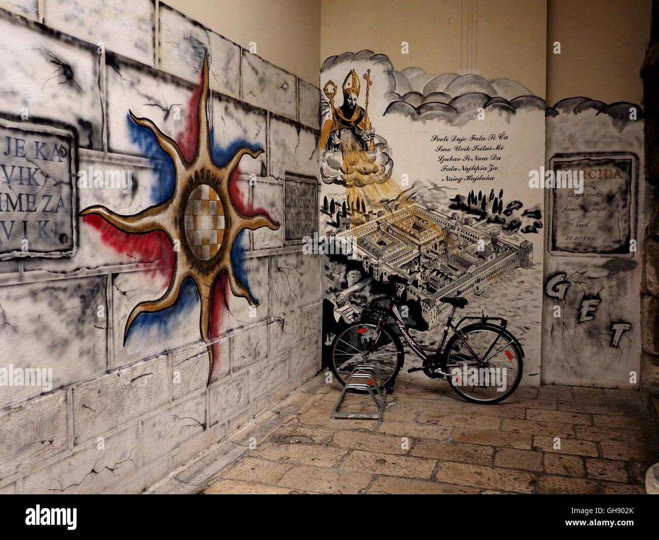 bicycle parked alongside street art on walls of old city in Split near ...