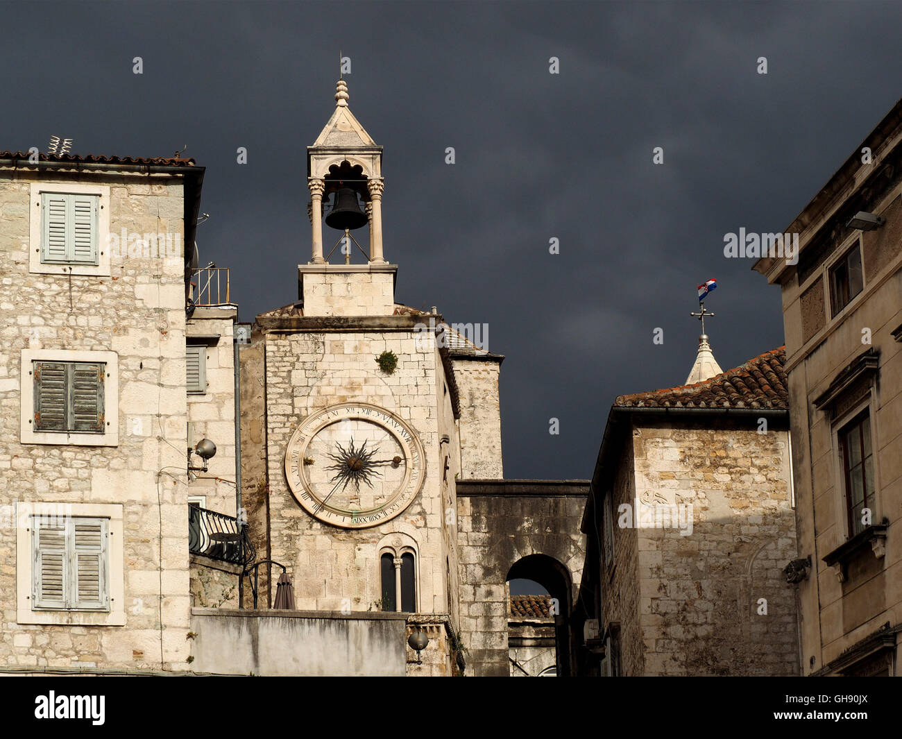 dark sky behind stone clock tower and shuttered windows of old stone ...