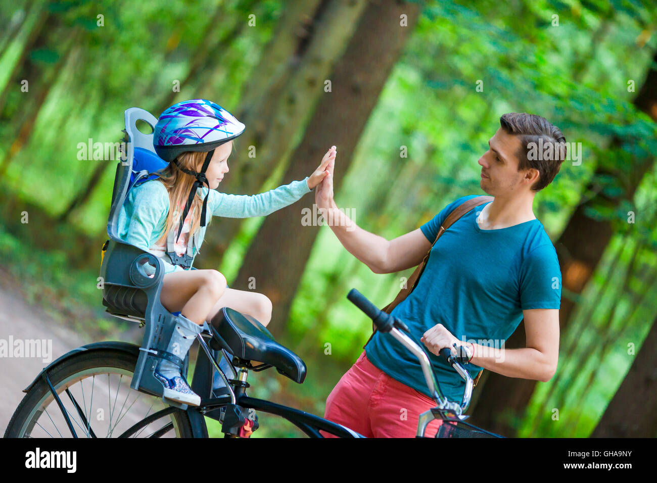 Happy family biking outdoors at the park Stock Photo - Alamy