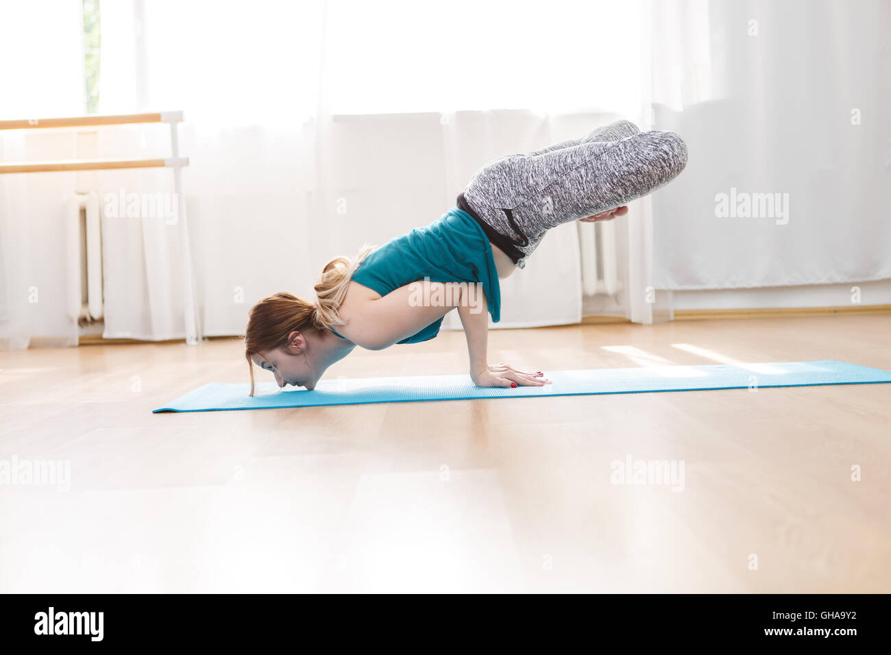 Flexible girl doing arm balancing mix exercises, lotus peacock position ...