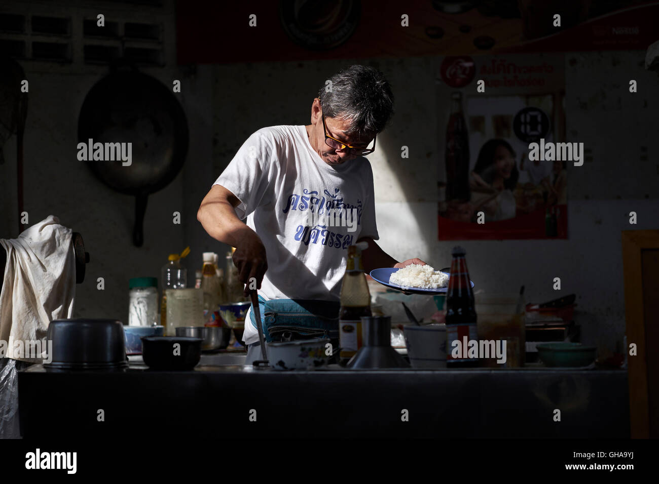 Chef cooking in the shadows at a back street alleyway cafe. Thailand S ...