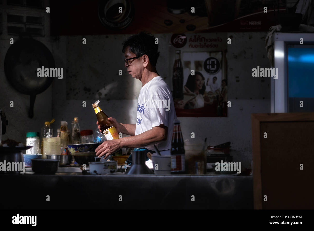 Chef cooking in the shadows at a back street alleyway cafe. Thailand S ...