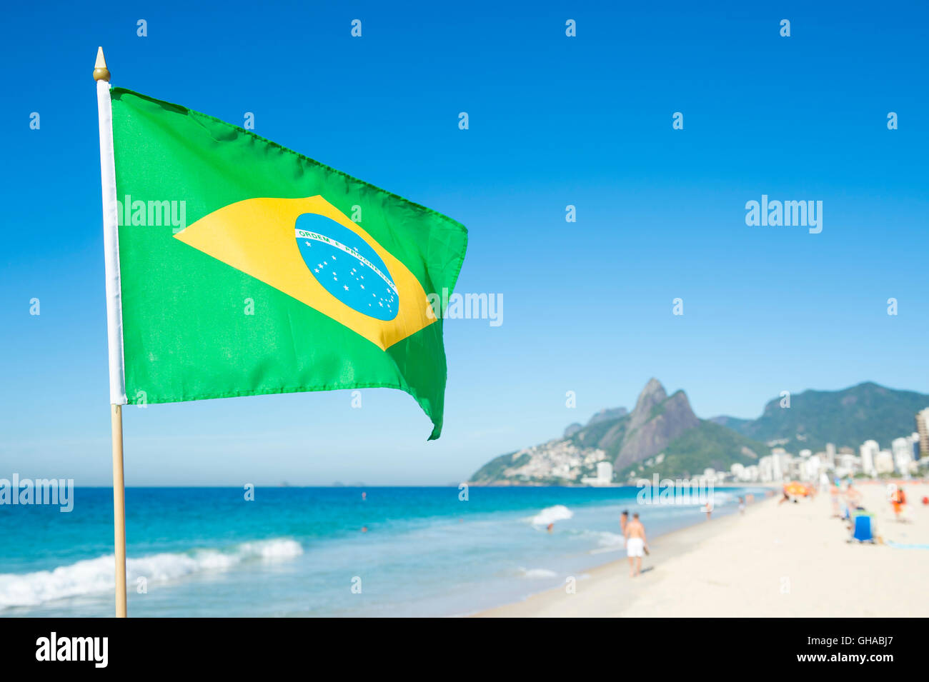Brazilian flag flying in bright sun above the city skyline at Ipanema ...
