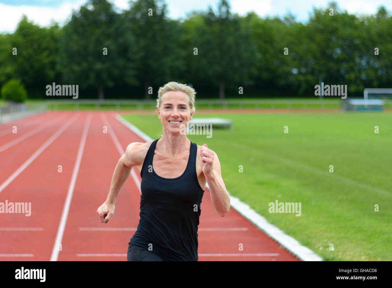 Healthy fit young woman running on a sports track at a stadium as she ...