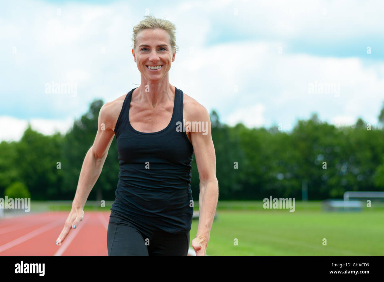 Healthy fit young woman running on a sports track at a stadium as she ...