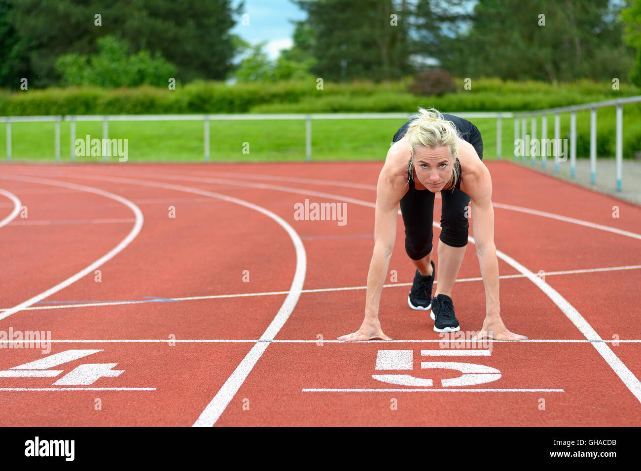 Athletic Woman Crouched Down In The Starter Position On A Race Track At