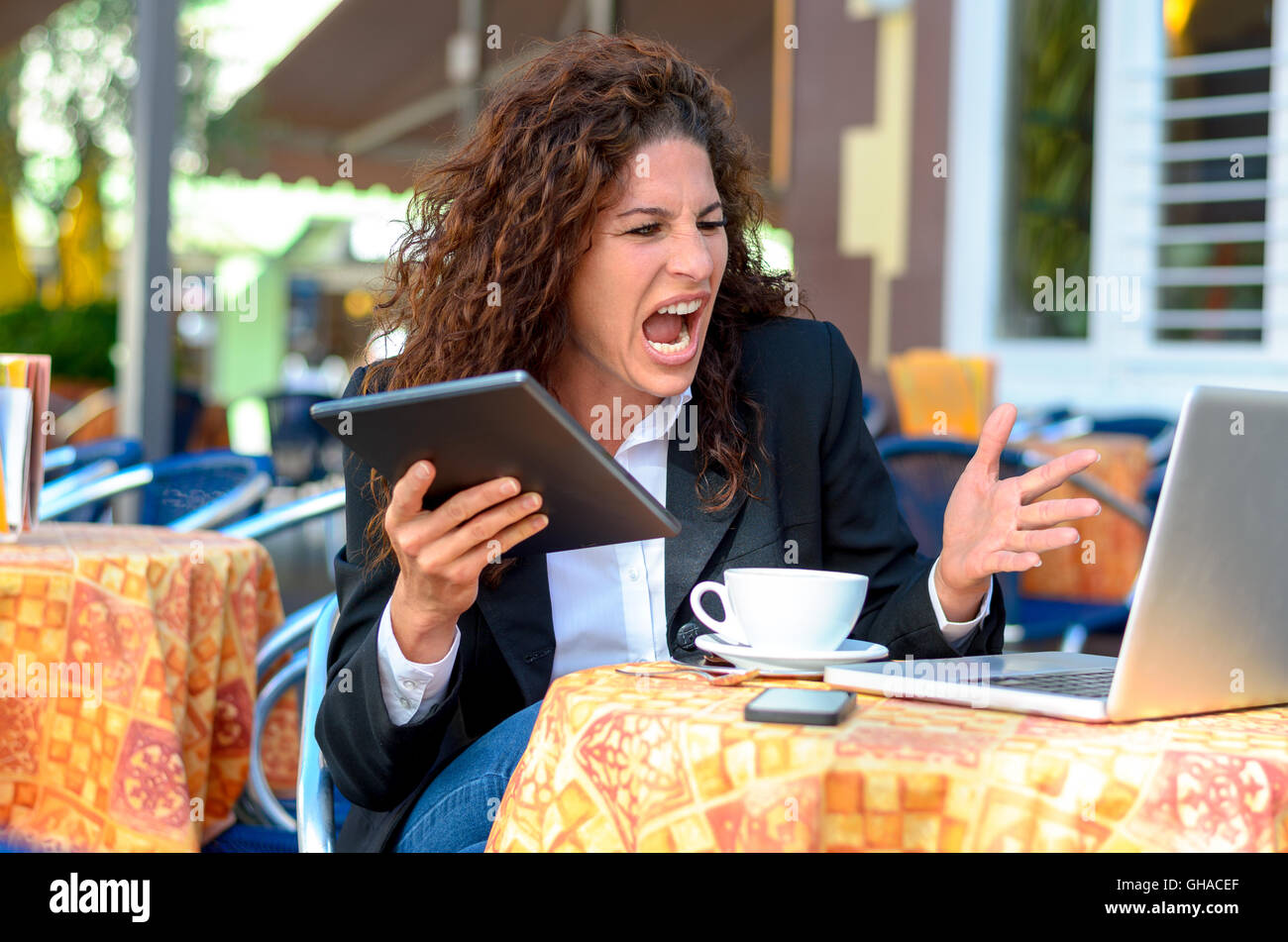 Angry frustrated young businesswoman yelling at her laptop computer as ...
