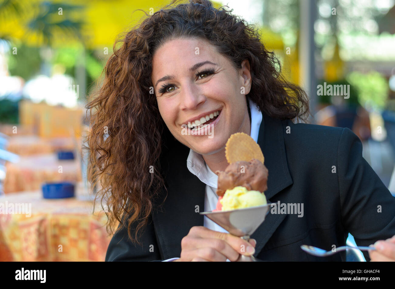 Attractive young woman with a large ice-cream sundae in a metal bowl ...