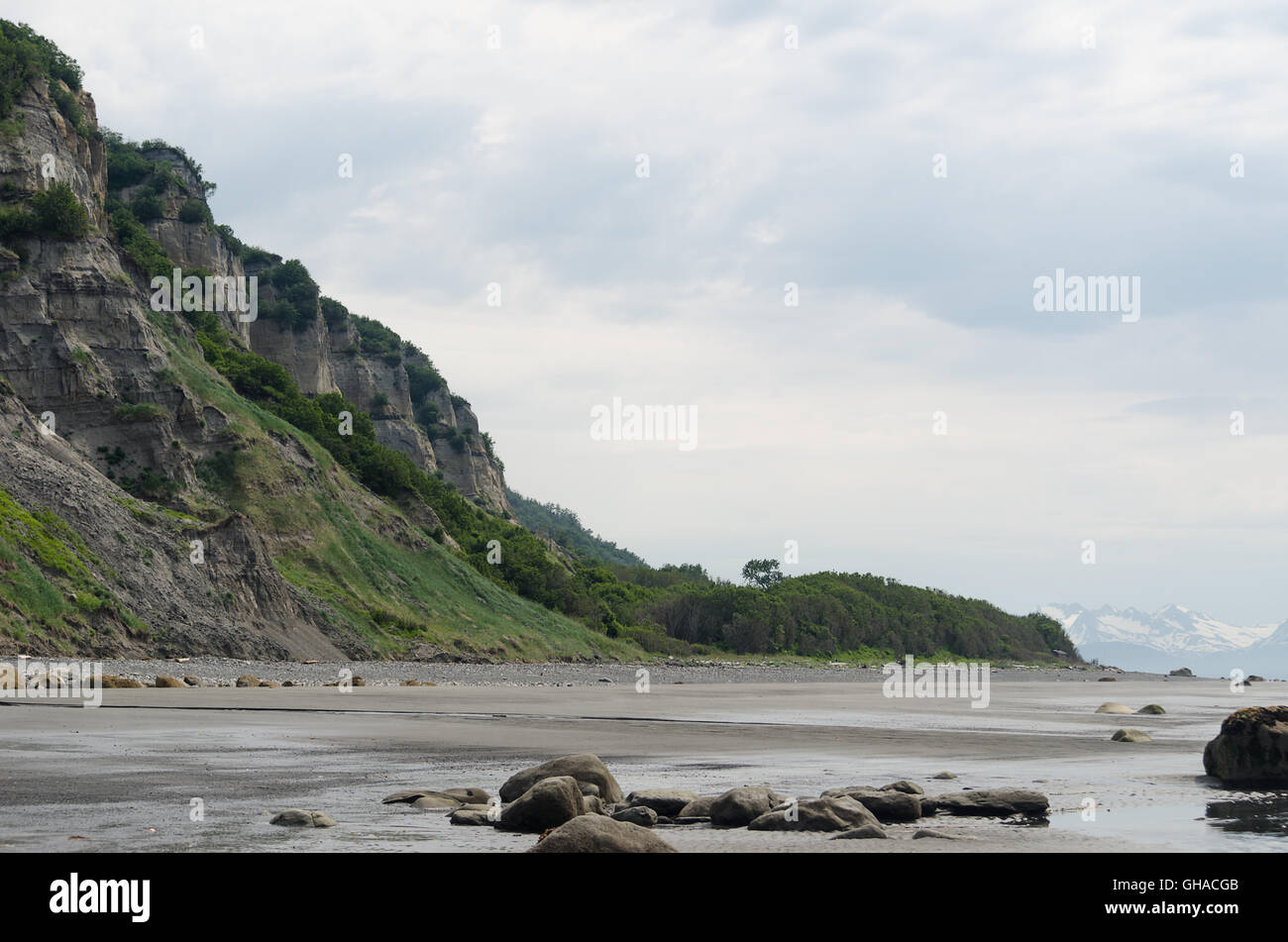 A high bluff covered in green sweeps down to a gravel beach near Homer ...