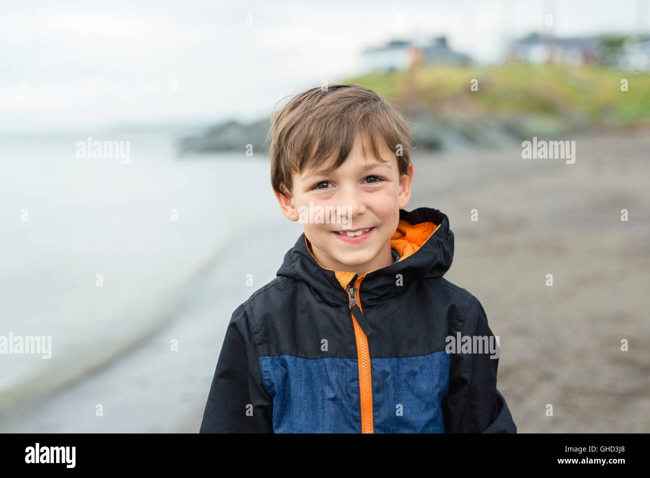 boy enjoying the rain and having fun outside on the beach a gray rainy ...