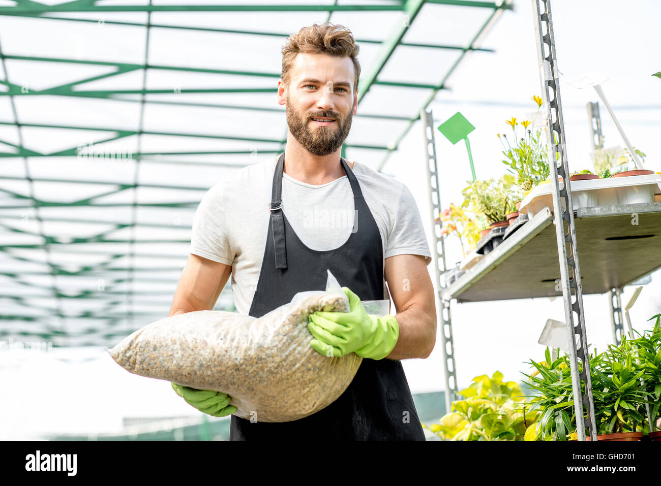 Handsome gardener with bag of soil Stock Photo - Alamy