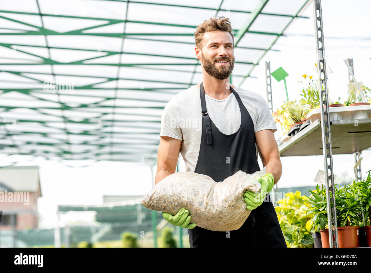 Handsome gardener with bag of soil Stock Photo - Alamy
