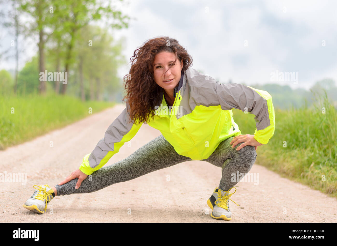 Sporty attractive young woman in a high visibility jacket doing ...