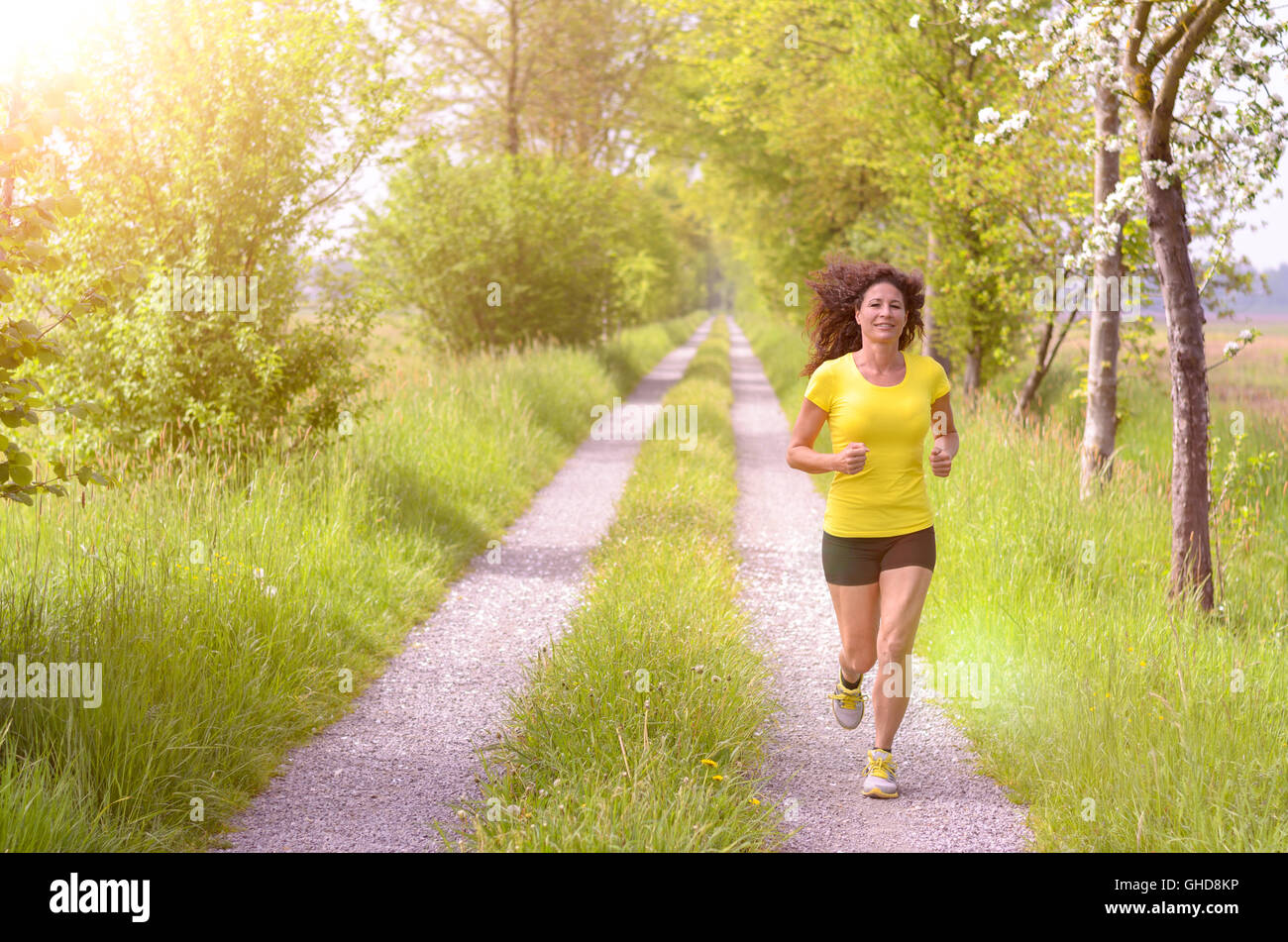 Active healthy young woman enjoying a morning run along a rural track ...