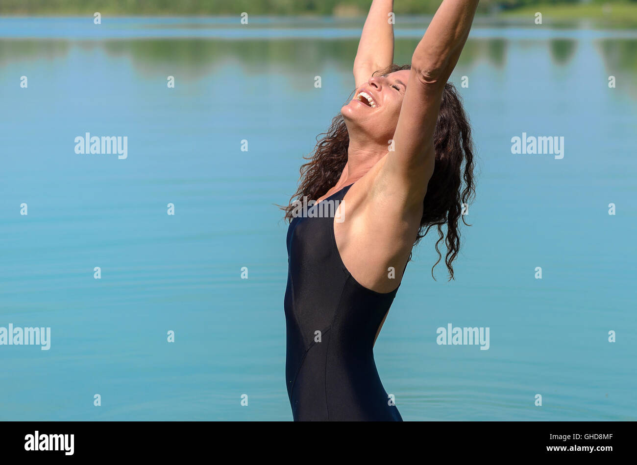 Beautiful single woman with big smile in bathing suit reaching up in ...
