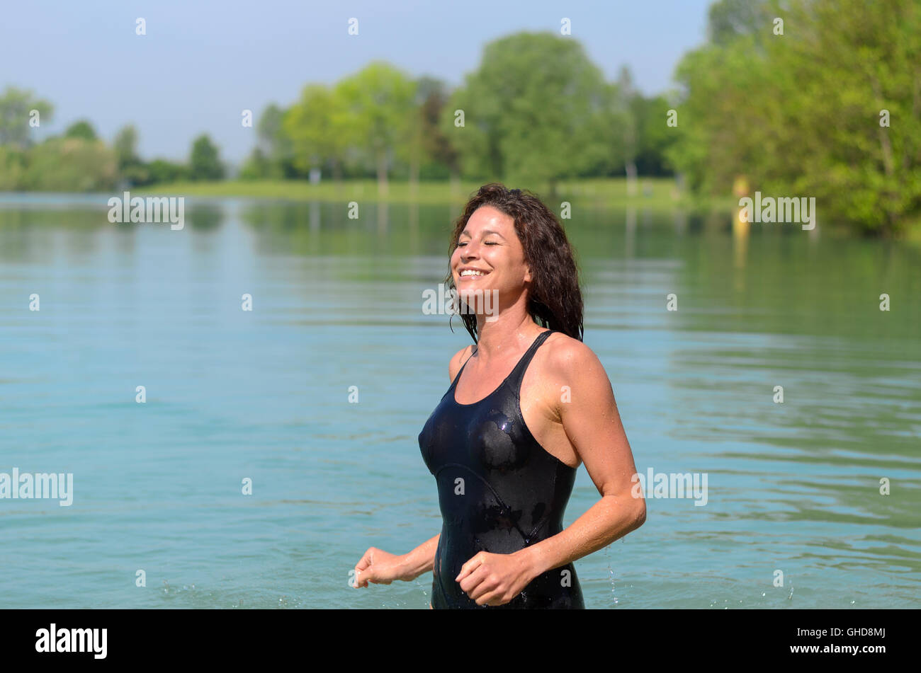 Beautiful single woman with joyous smile in bathing suit wading in ...