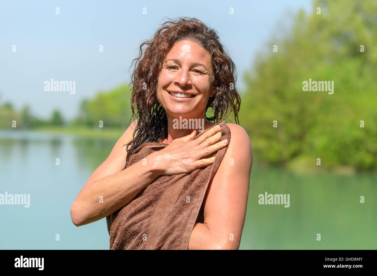 Attractive woman drying herself with a towel after swimming in a rural ...