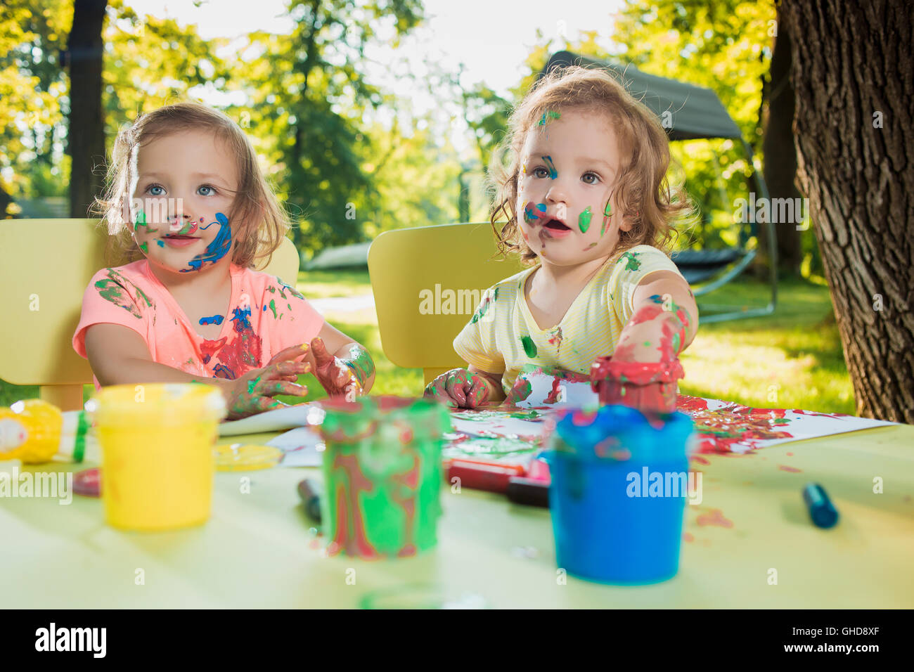Two-year old girls painting with poster paintings together against ...